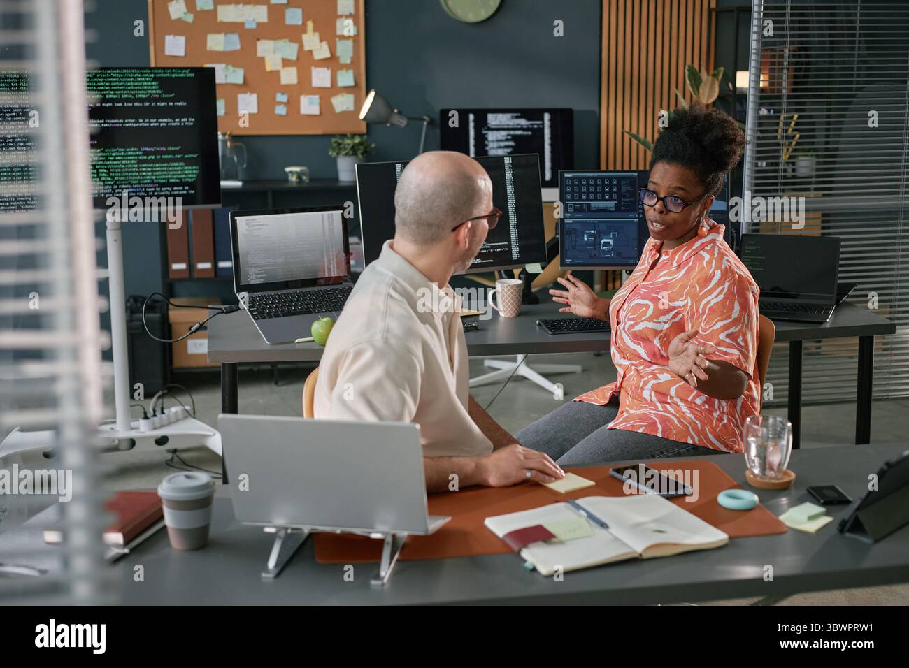 Black woman discussing project with Caucasian middle aged man in modern ...