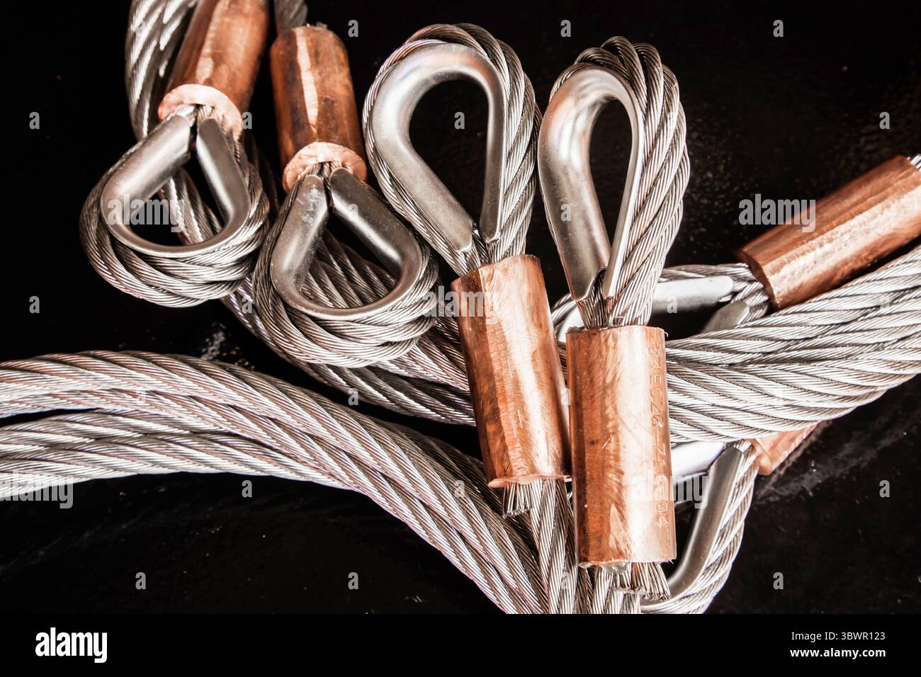 Stainless steel cable, with loops and copper clamps, and a black ...