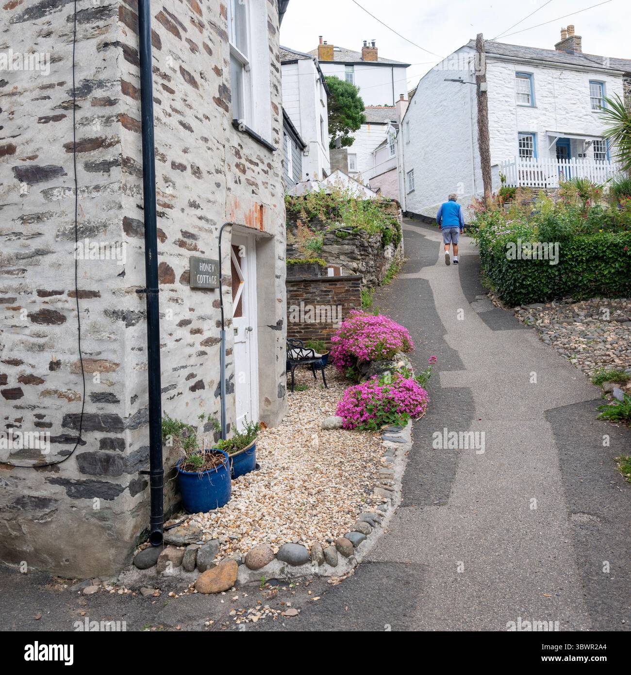 man walks on narrow street near old white washed houses in cornish ...