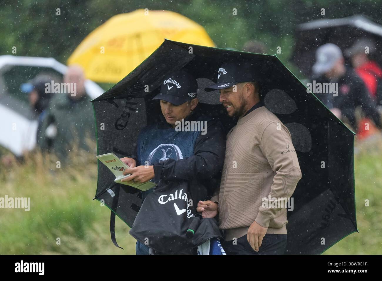 Xander Schauffele of the United States checks his notes with his caddie ...