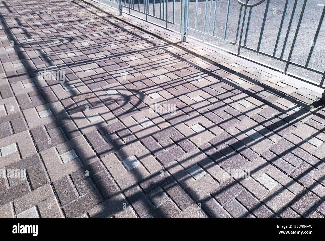 Metal fence casting intricate shadows across gray and white tiled ...