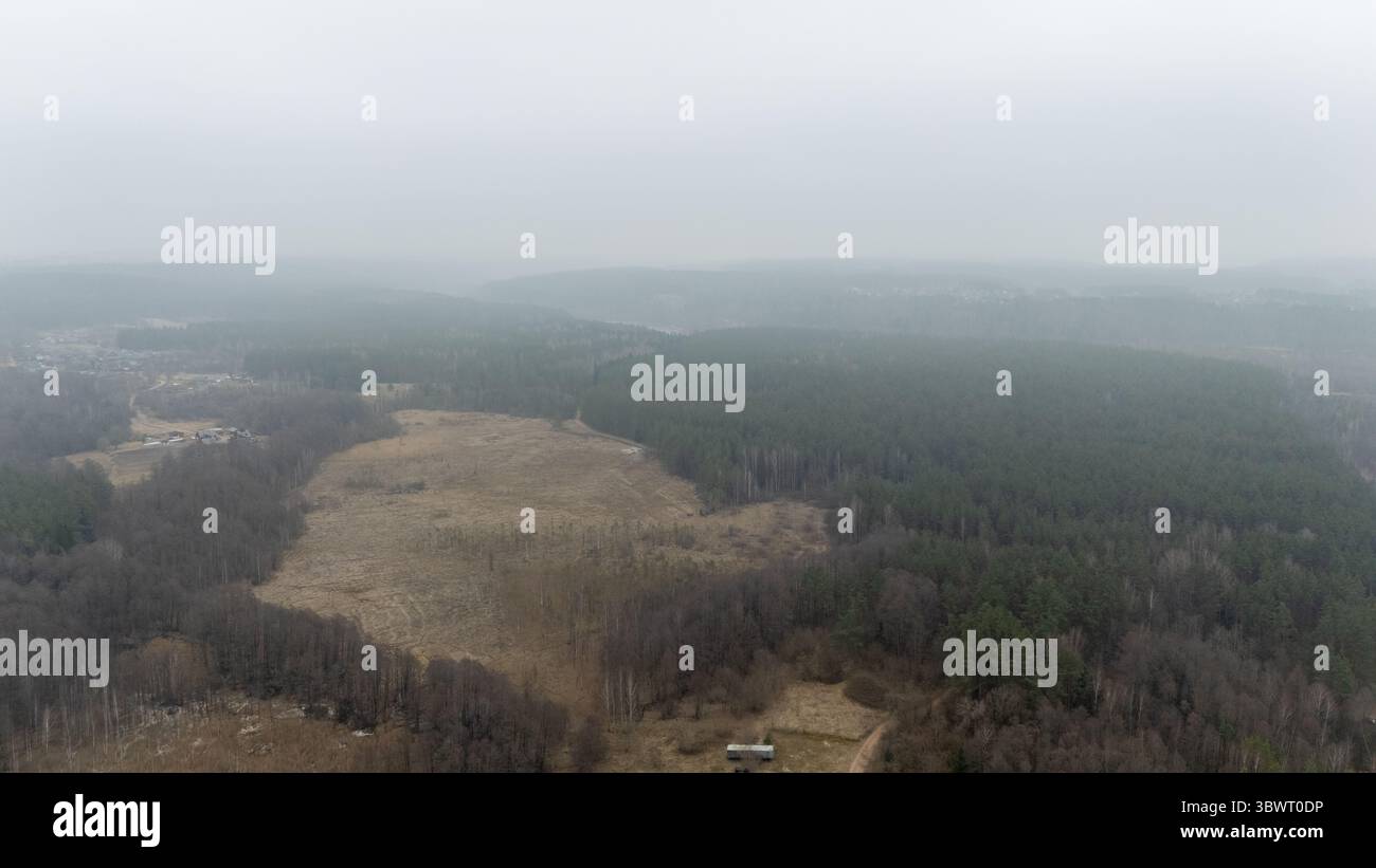 Aerial view of a foggy landscape with dense forests and open fields ...