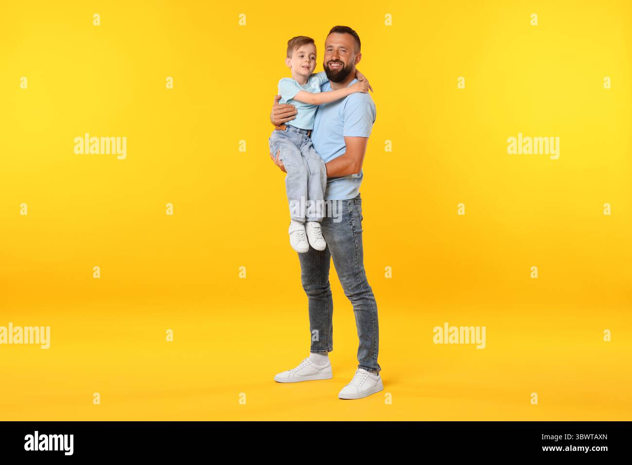 Family. Happy father and his son on yellow background Stock Photo - Alamy