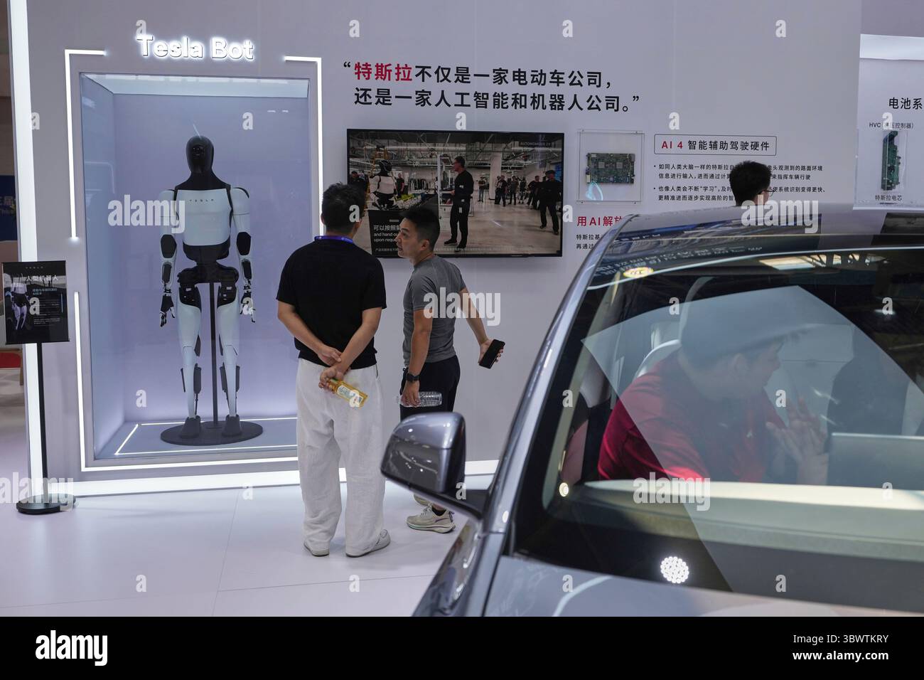 Visitors look at the Optimus, also known as Tesla Bot, a robotic ...