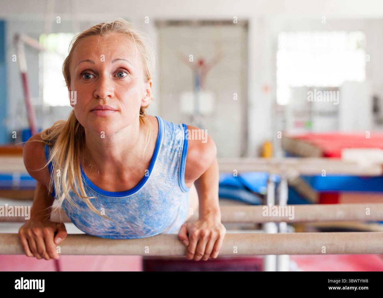 Woman gymnast performs complex acrobatic exercise on parallel bars in gym Stock Photo - Alamy