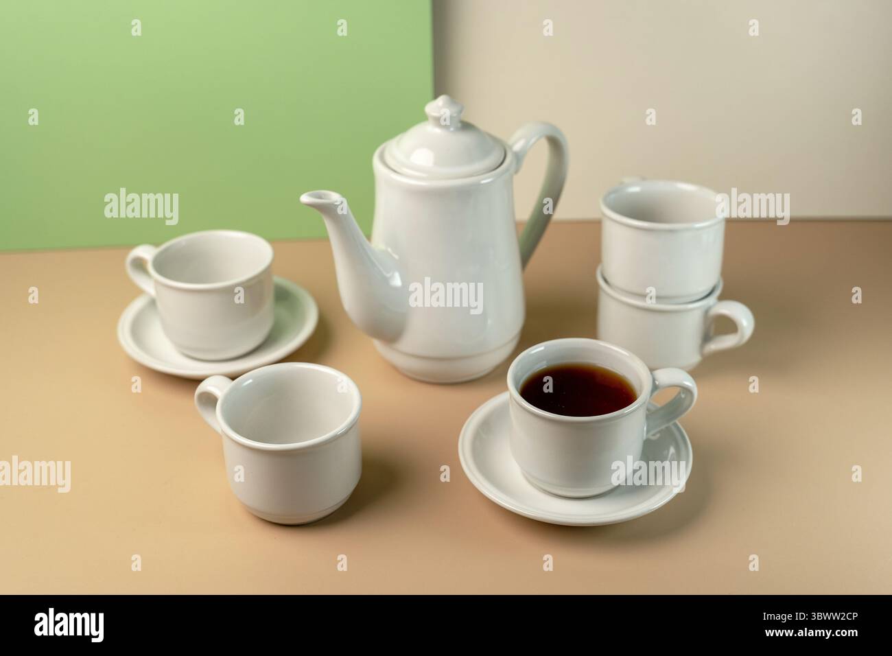 White ceramic tea set with a teapot and stackable cups. One cup is ...