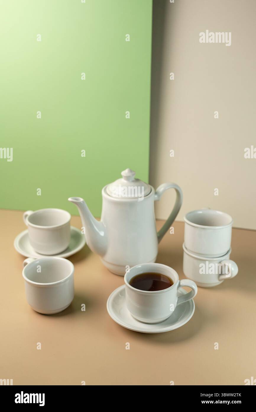 White ceramic tea set with a teapot and stackable cups. One cup is ...