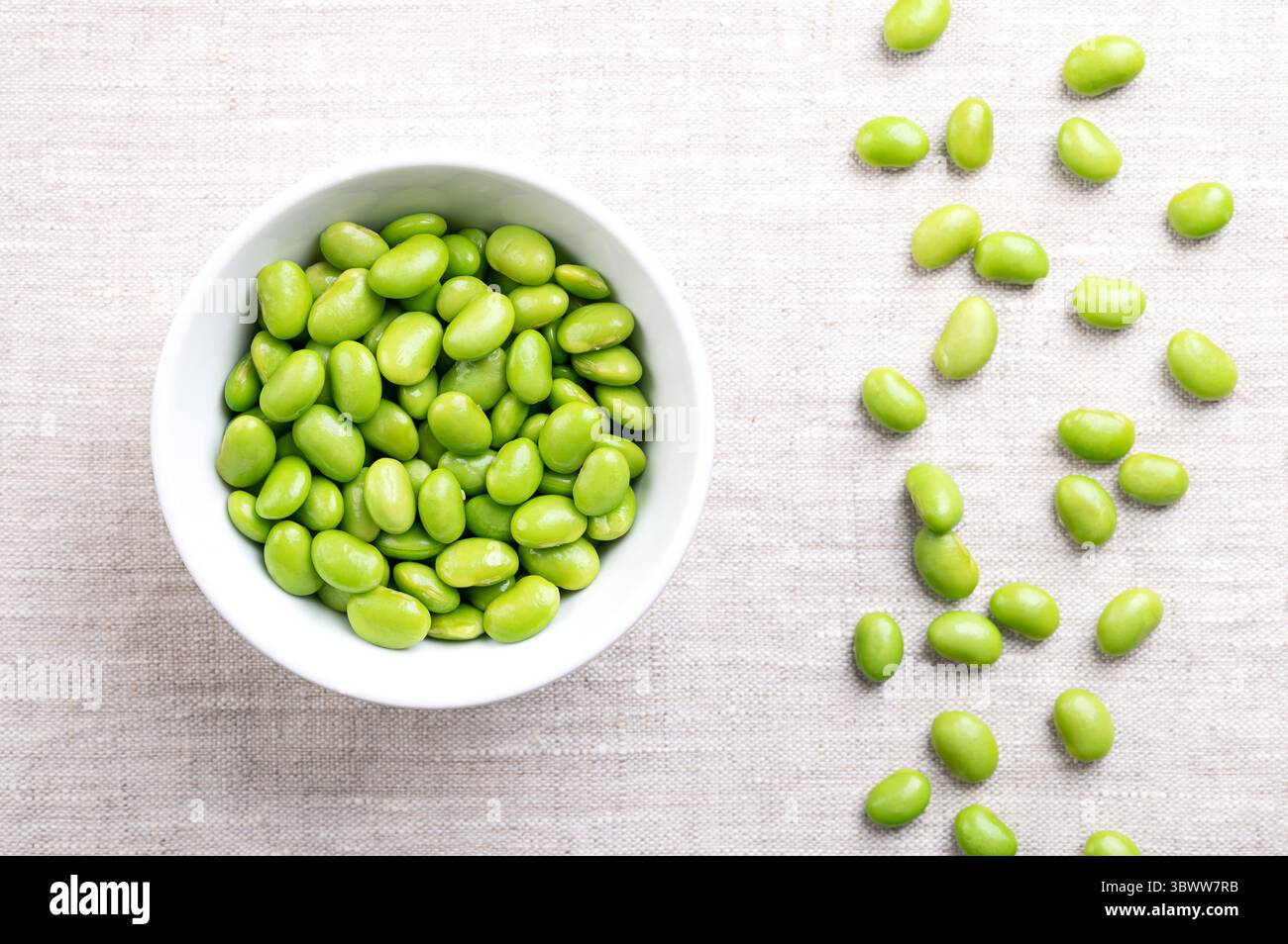 Edamame beans in a white bowl on linen. Shelled young, immature ...