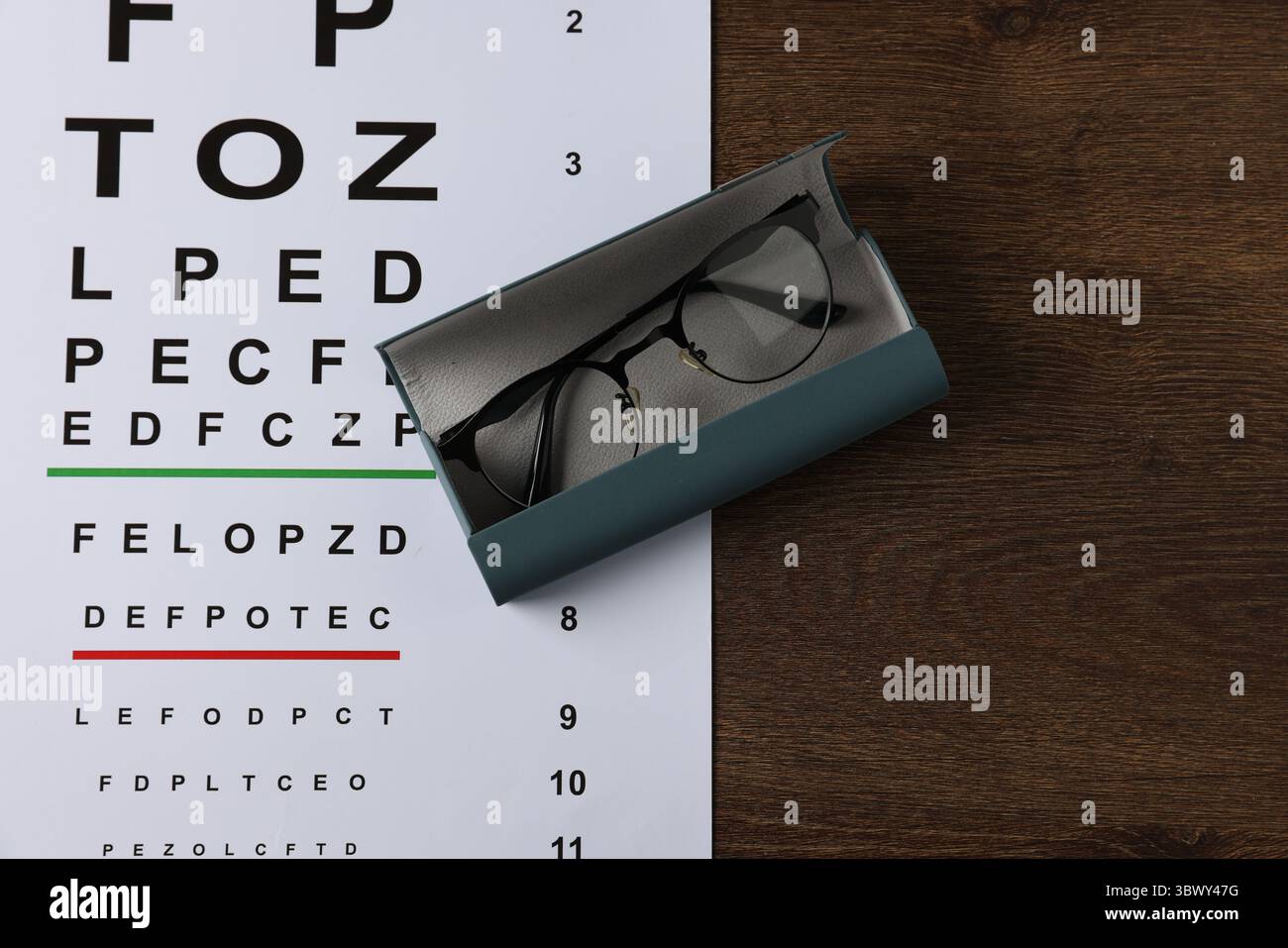 Vision test chart, glasses and case on wooden table, top view Stock ...