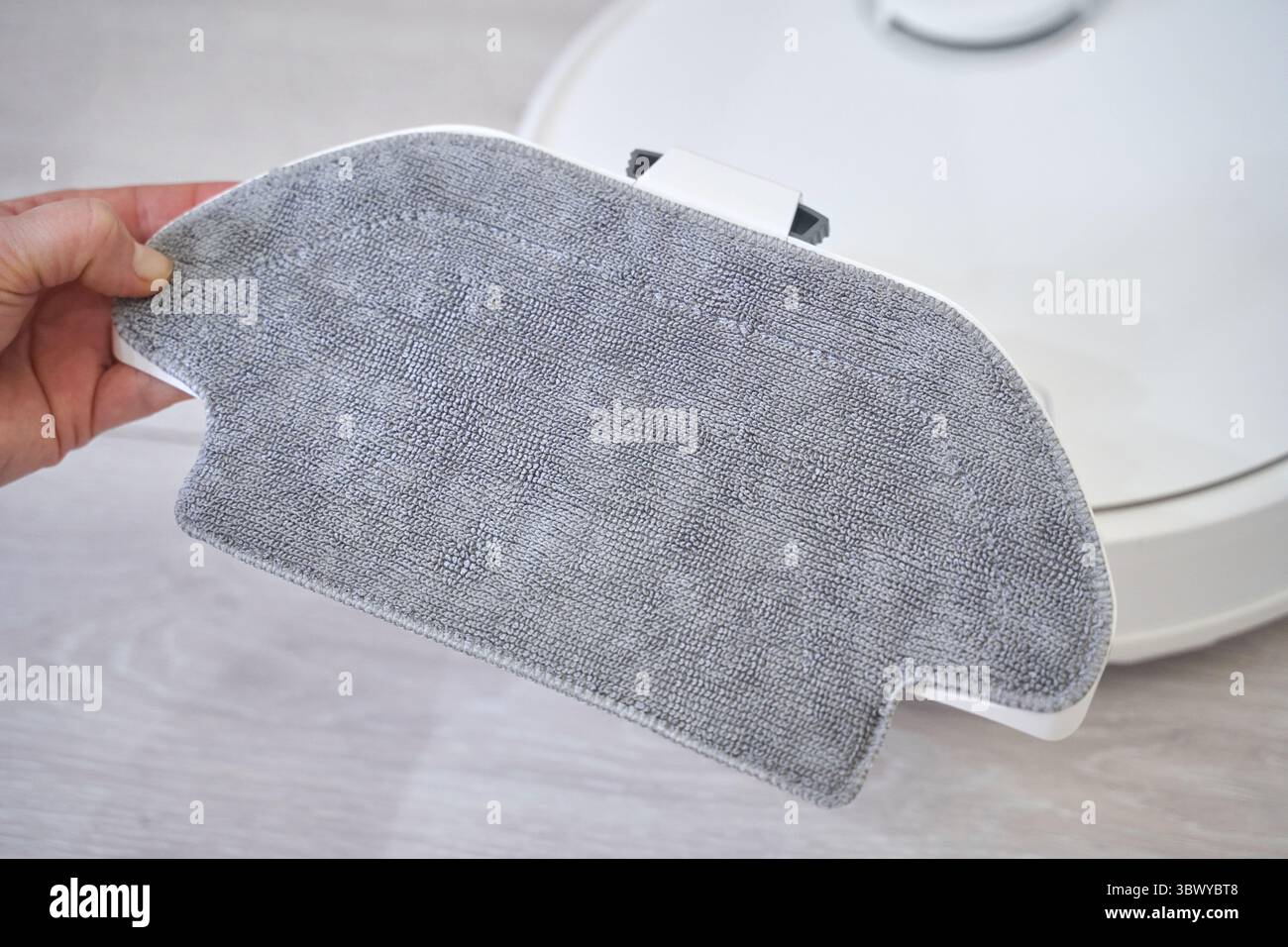 Hand holding robotic vacuum mop attachment for efficient home cleaning ...