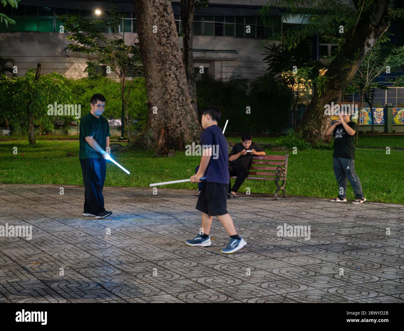 Boys engaging in sword fighting at Tao Dan Park at night in Ho Chi Minh ...