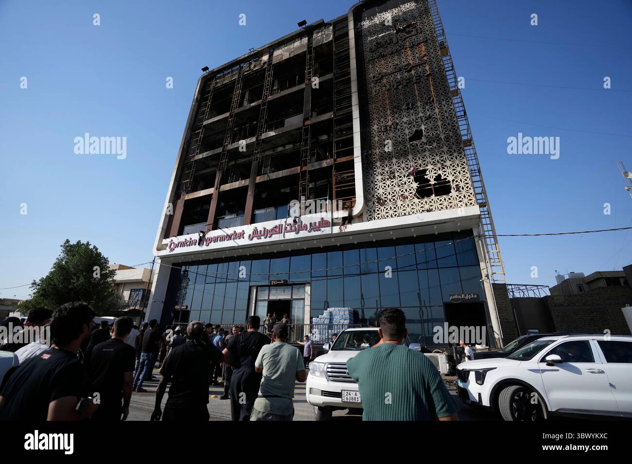 Iraqi people gather in front of a burning hypermarket building in Kut ...