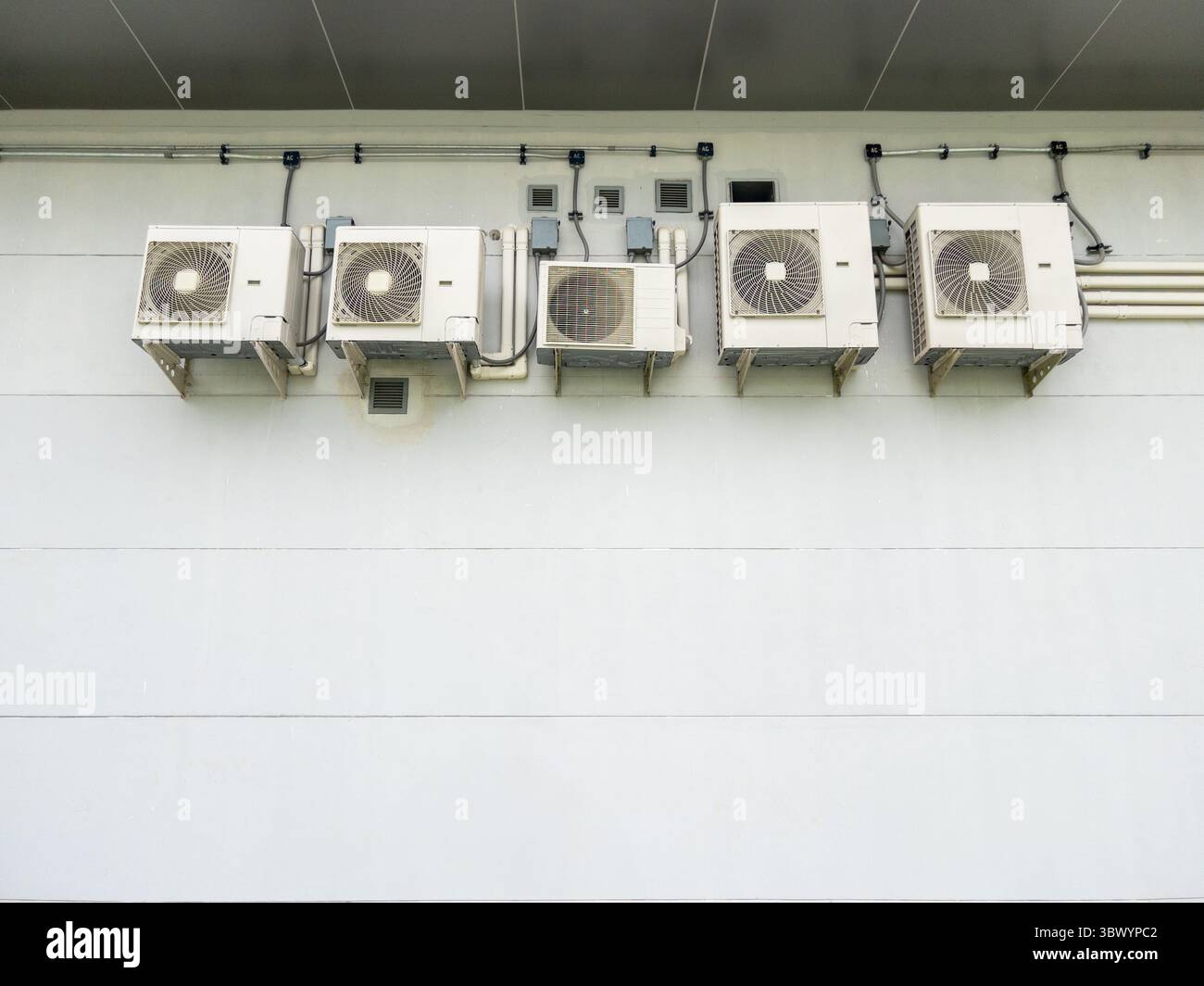 Air conditioner compressors on a train power control building wall ...