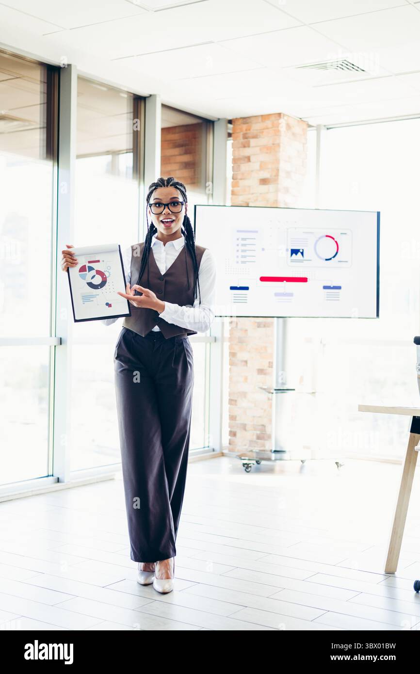 Professional businesswoman presenting data in modern office setting ...