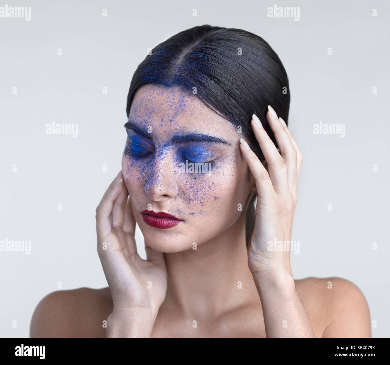 A modern beauty portrait of a mixed-race Middle Eastern woman with eyes closed and blue pigment ...