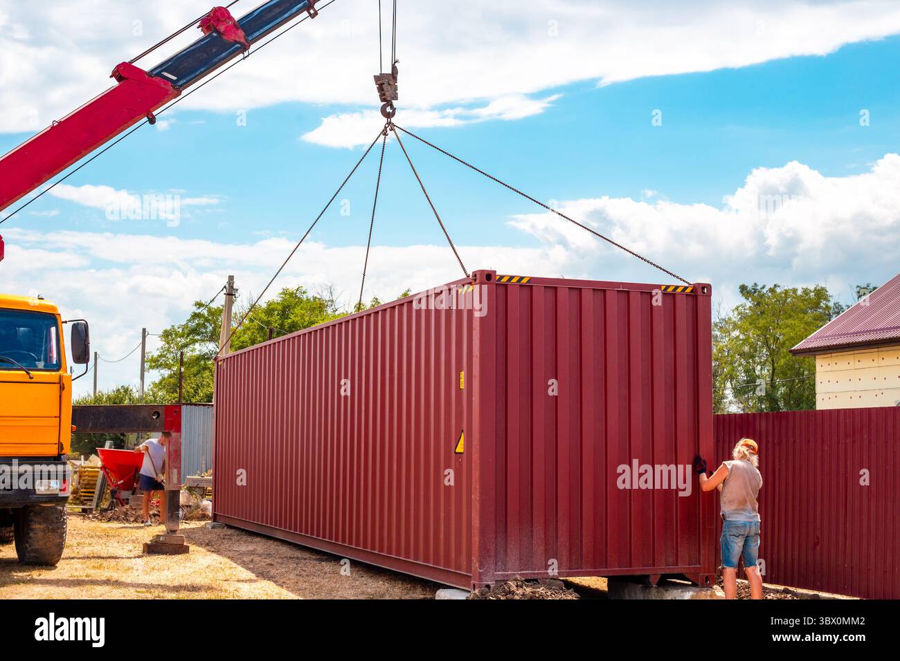 Red crane lifts red cargo container ready to be installed on ...