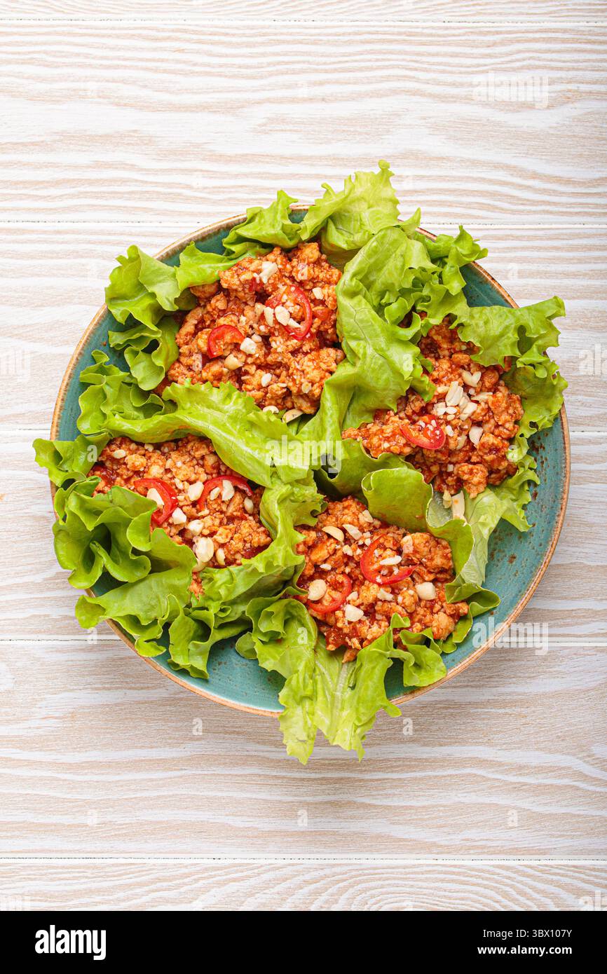 Lettuce wraps filled with minced meat and topped with peanuts and chili ...