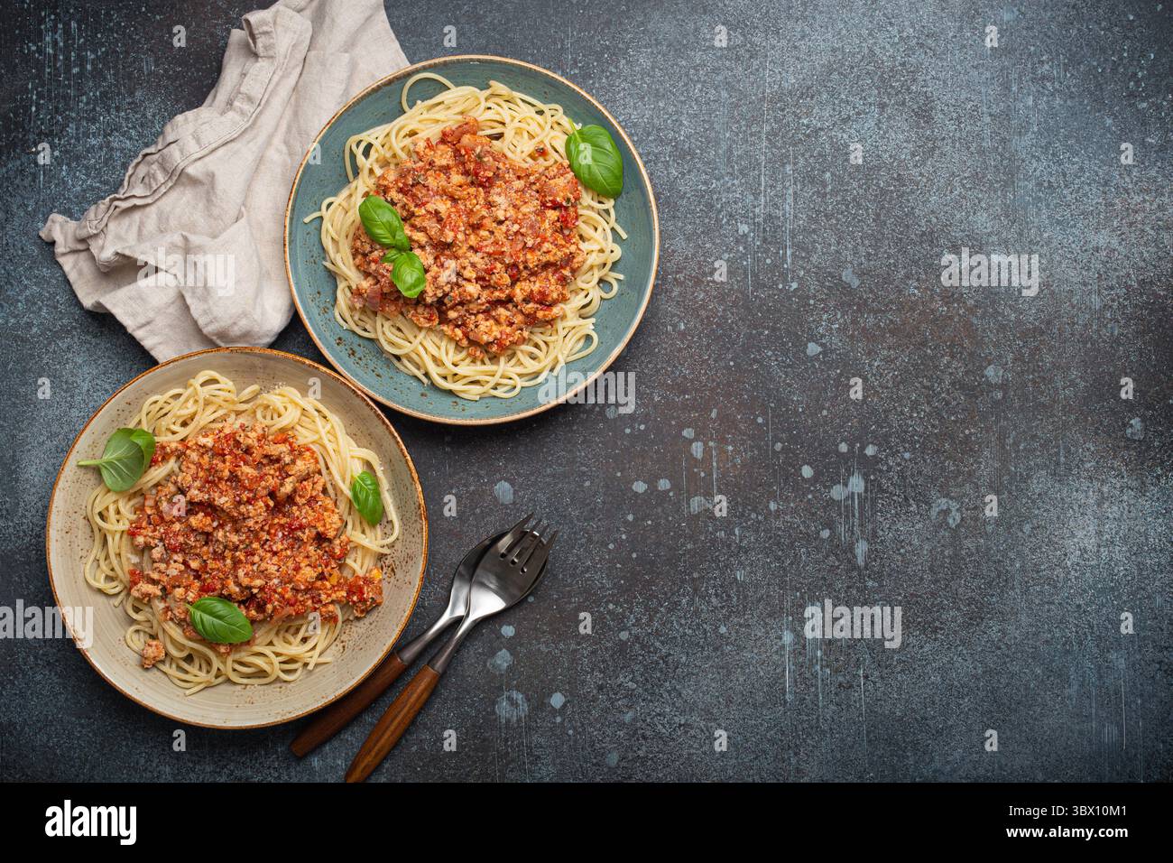 Two plates of spaghetti bolognese with basil on dark background with ...
