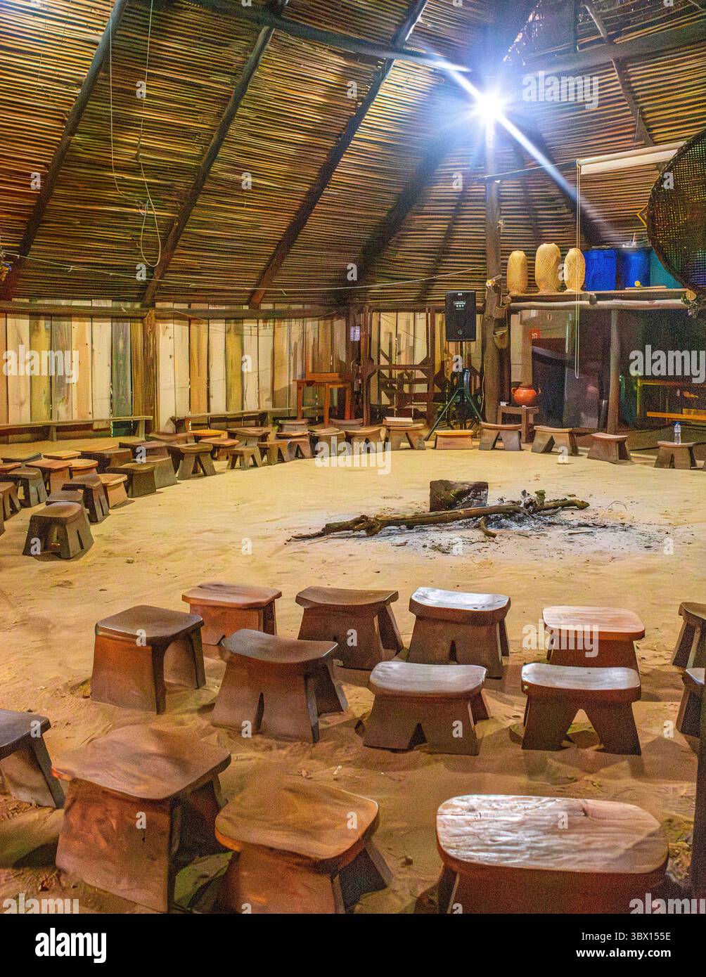 Interior view of a round traditional gathering space with wooden stools ...