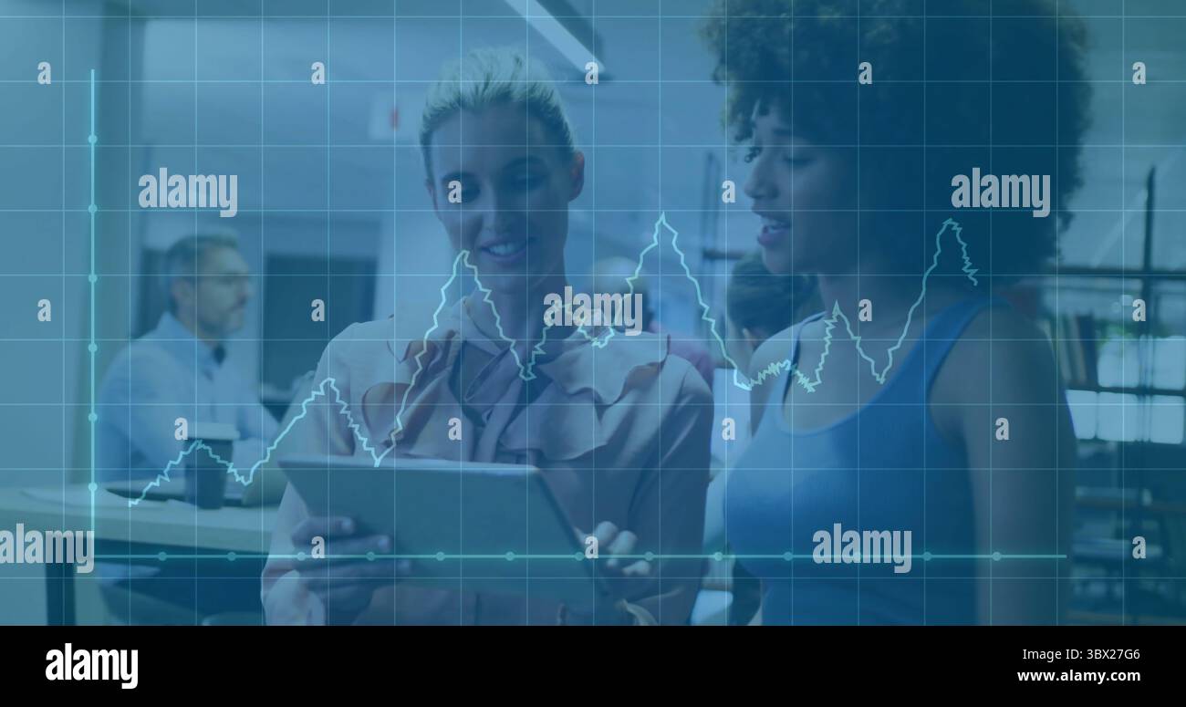 Two colleagues reviewing data on tablet in office, with coworker using ...