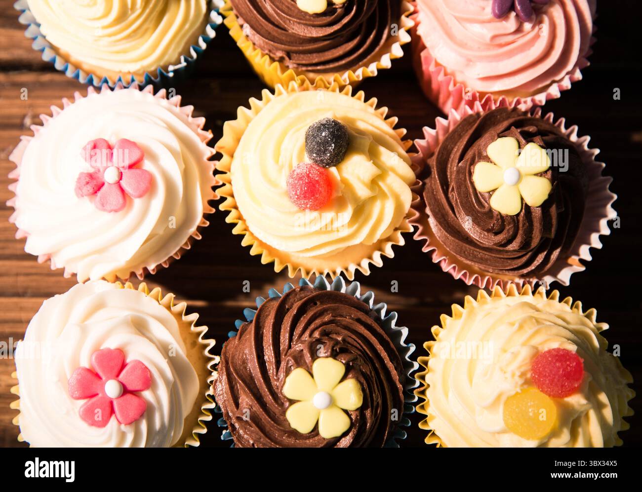 Nine cupcakes are sitting in flat design on wood tabletop with pastel ...