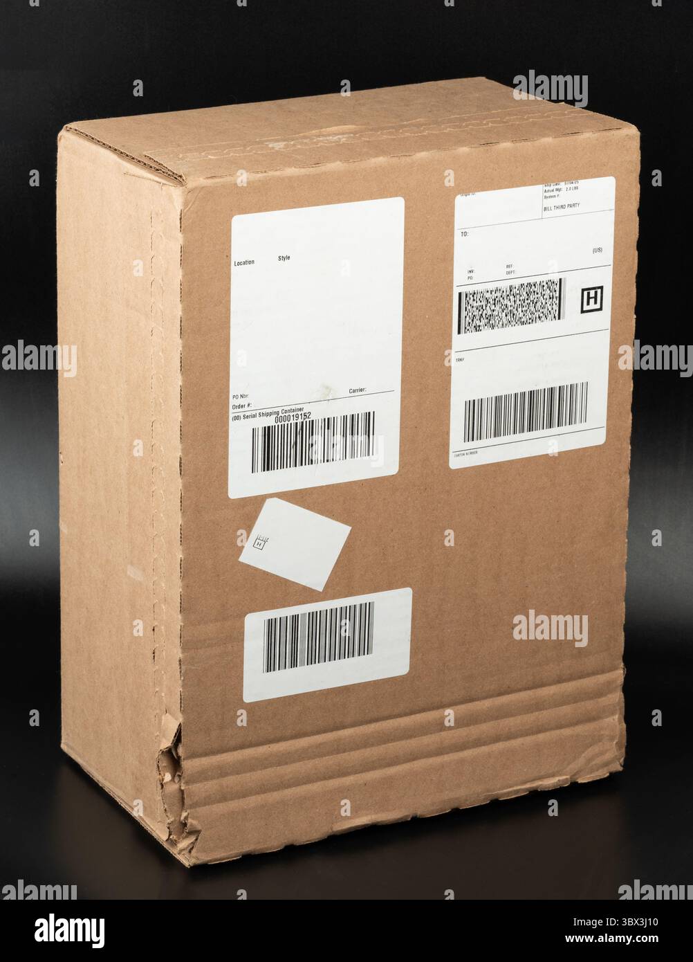 Cardboard delivery box sits on dark surface, marked with shipping ...