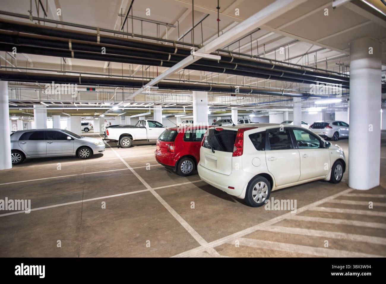 underground concrete parking with sedan cars, bakkie and small truck in ...