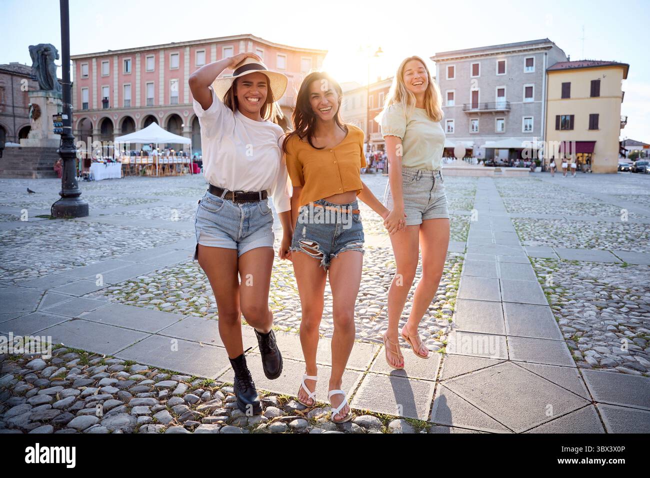 Three young women holding hands and walking in a town square Stock ...