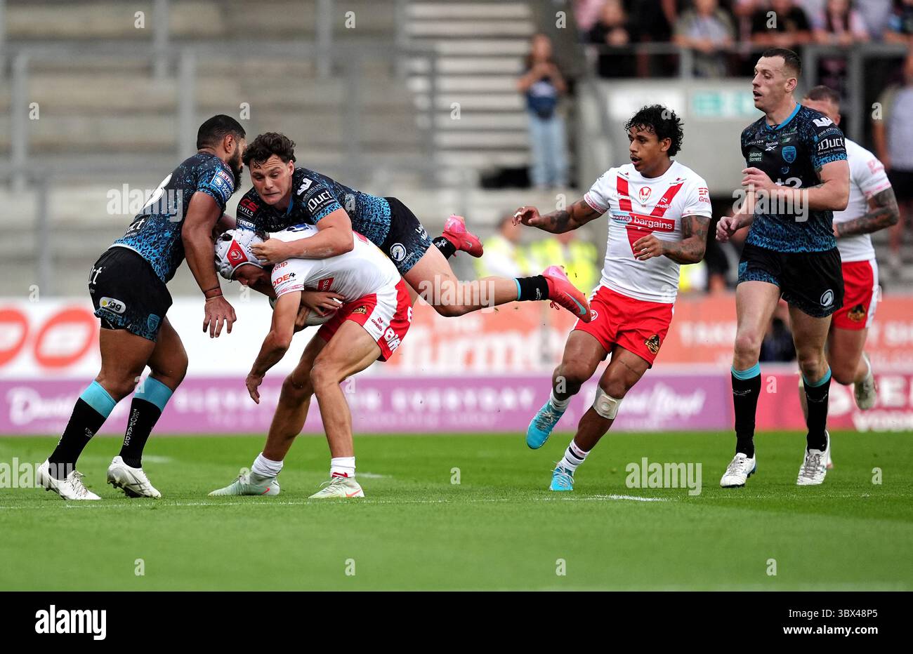 St Helens' Harry Robertson (centre) is tackled by Leigh Leopards' Isaac ...