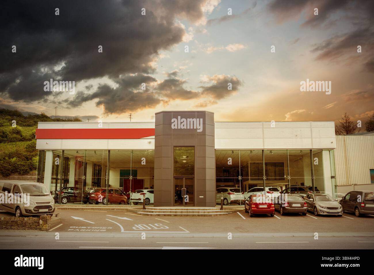 Cars by building against cloudy sky during sunset Stock Photo - Alamy