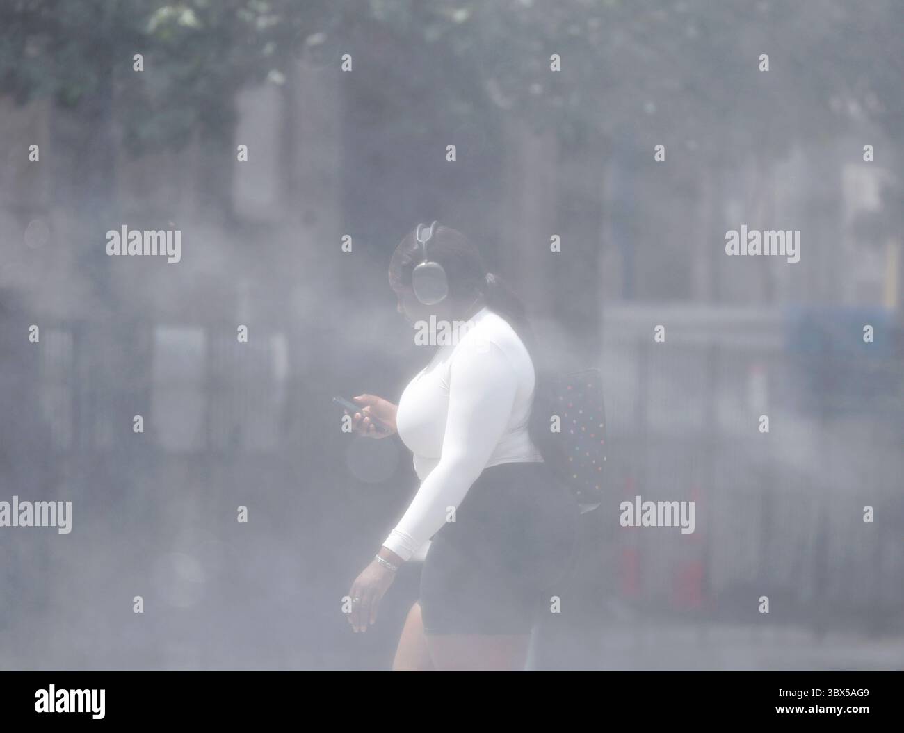 A pedestrian walks by the water coming out of an open fire hydrant in ...