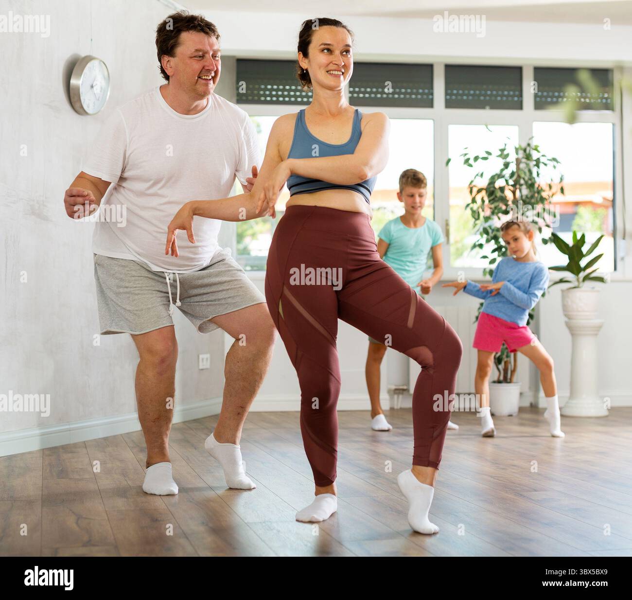 Mother and father learning dynamic boogie-woogie in pair in dance studio during family class ...