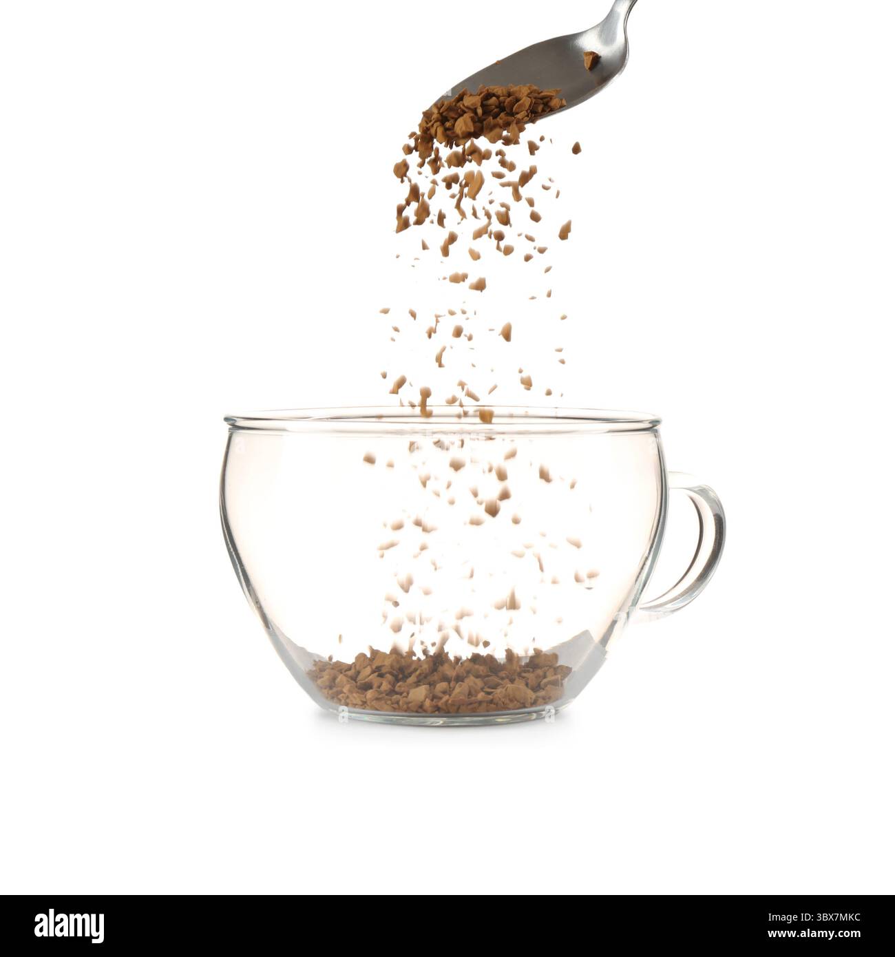 Adding granulated instant coffee from spoon into glass cup isolated on ...