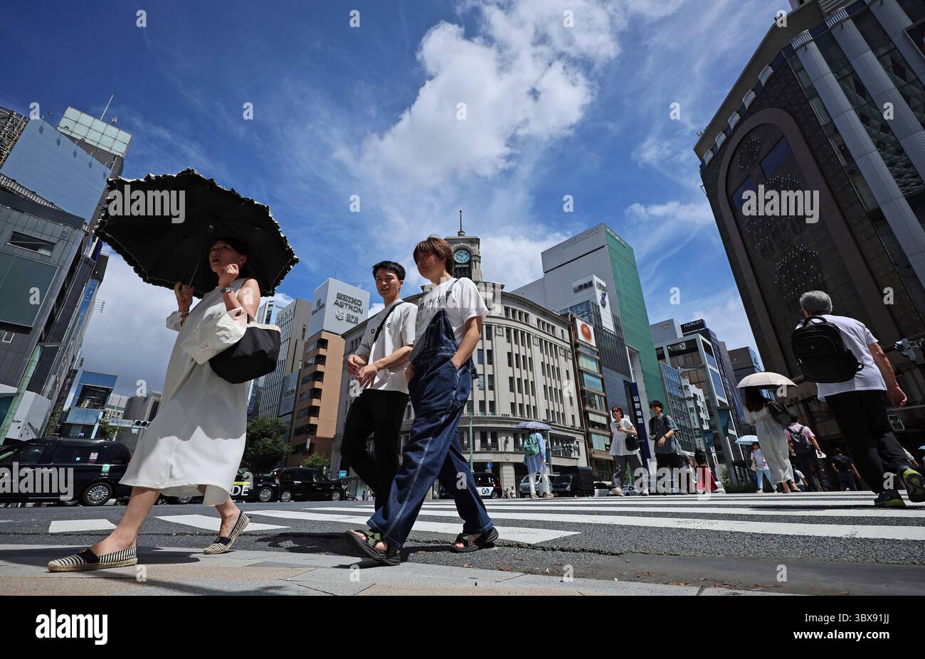 People walk under the strong sunlight in Tokyo, Japan, July 18, 2025 ...