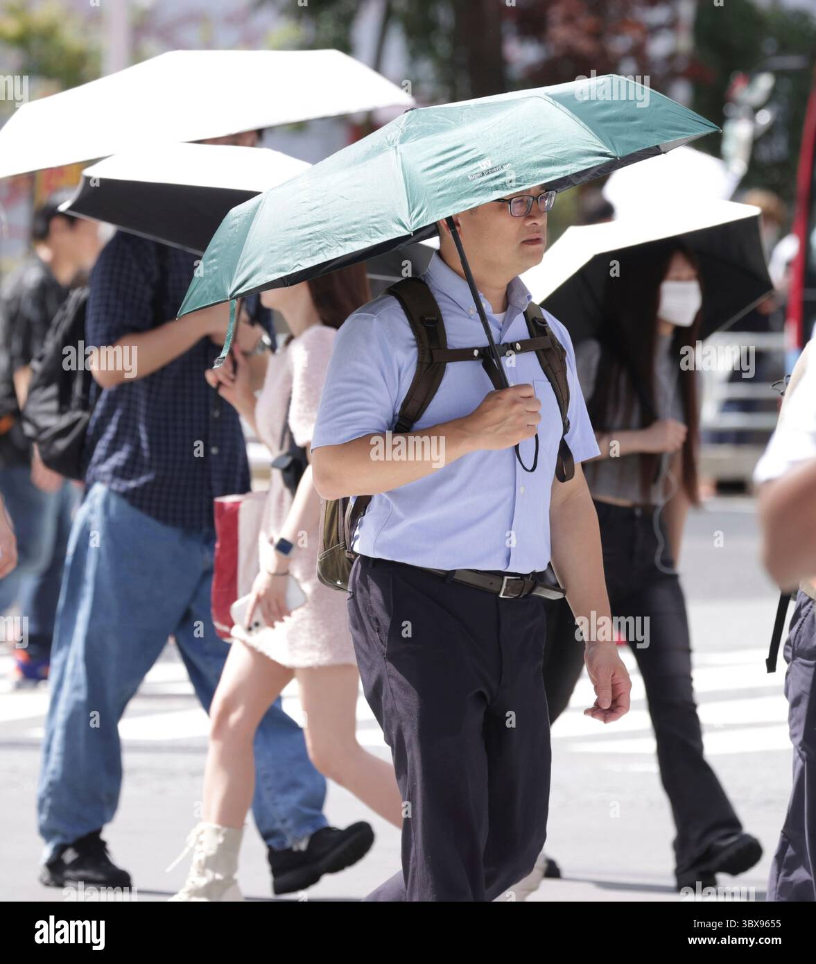 People walk under the strong sunlight in Tokyo, Japan, July 18, 2025 ...