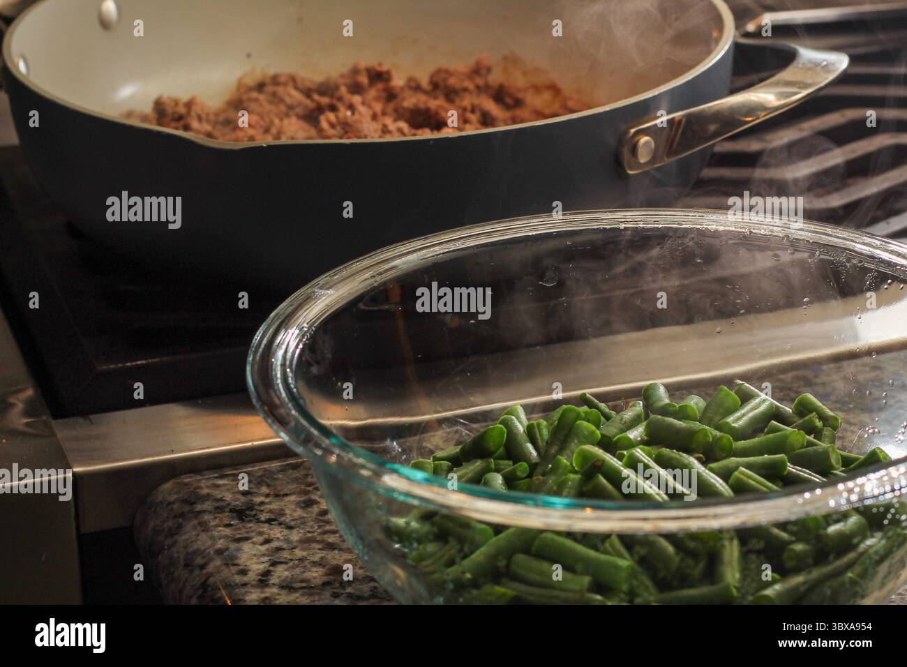 Steamed cut green beans with sauteing beef on stovetop Stock Photo - Alamy