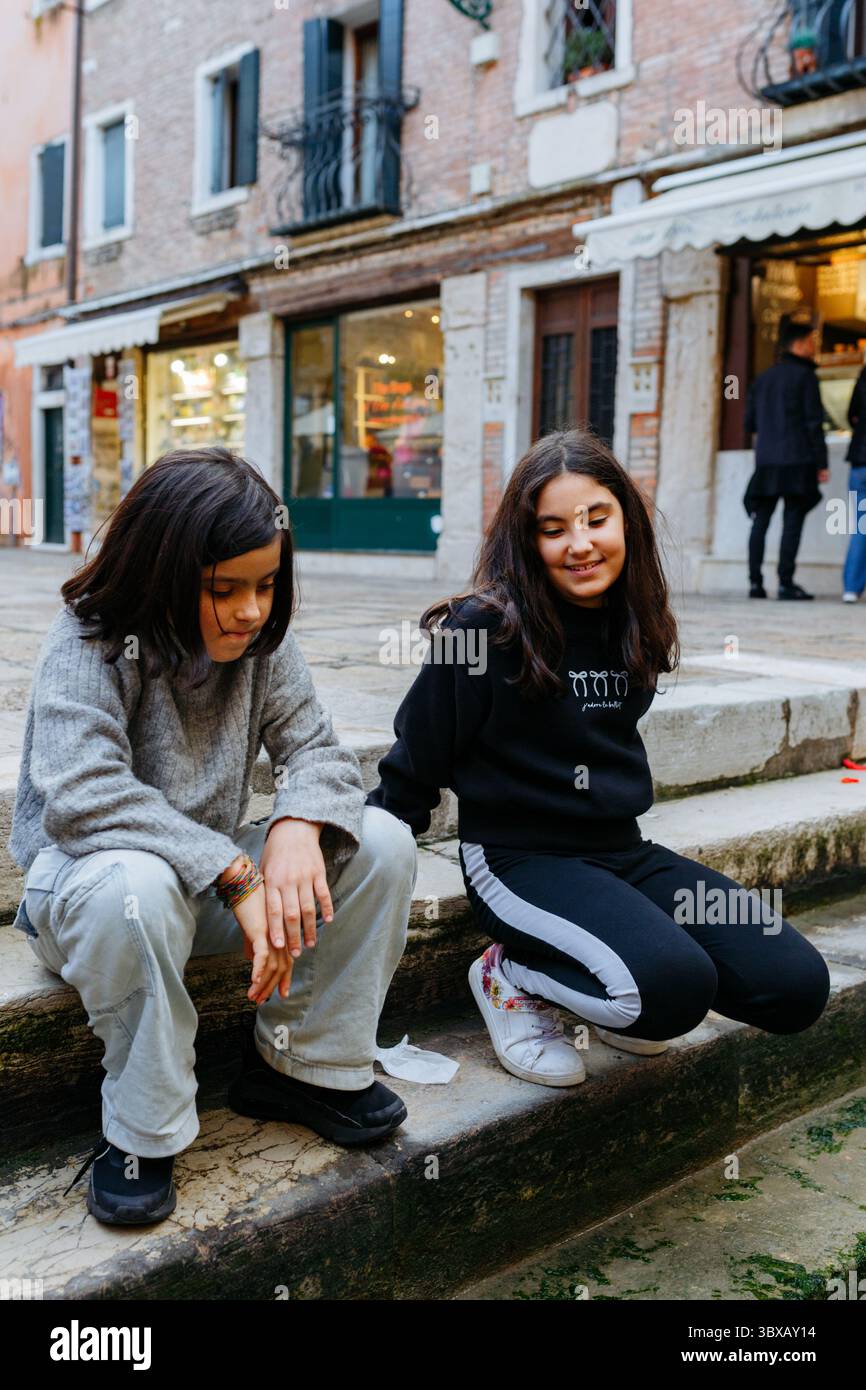two girls sitting on the stairs of a square in Venice Stock Photo - Alamy
