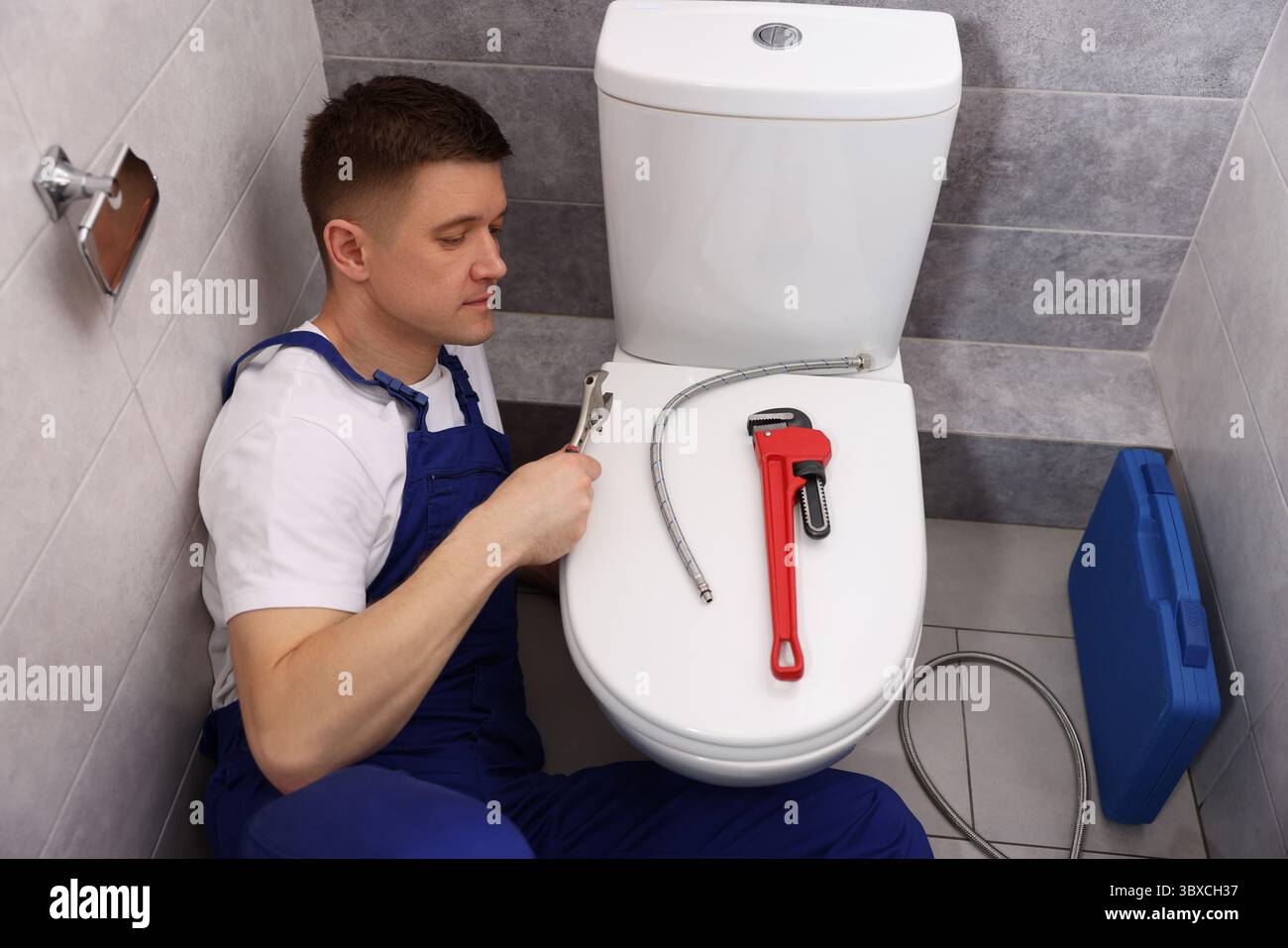 Professional plumber fixing toilet bowl in restroom Stock Photo - Alamy