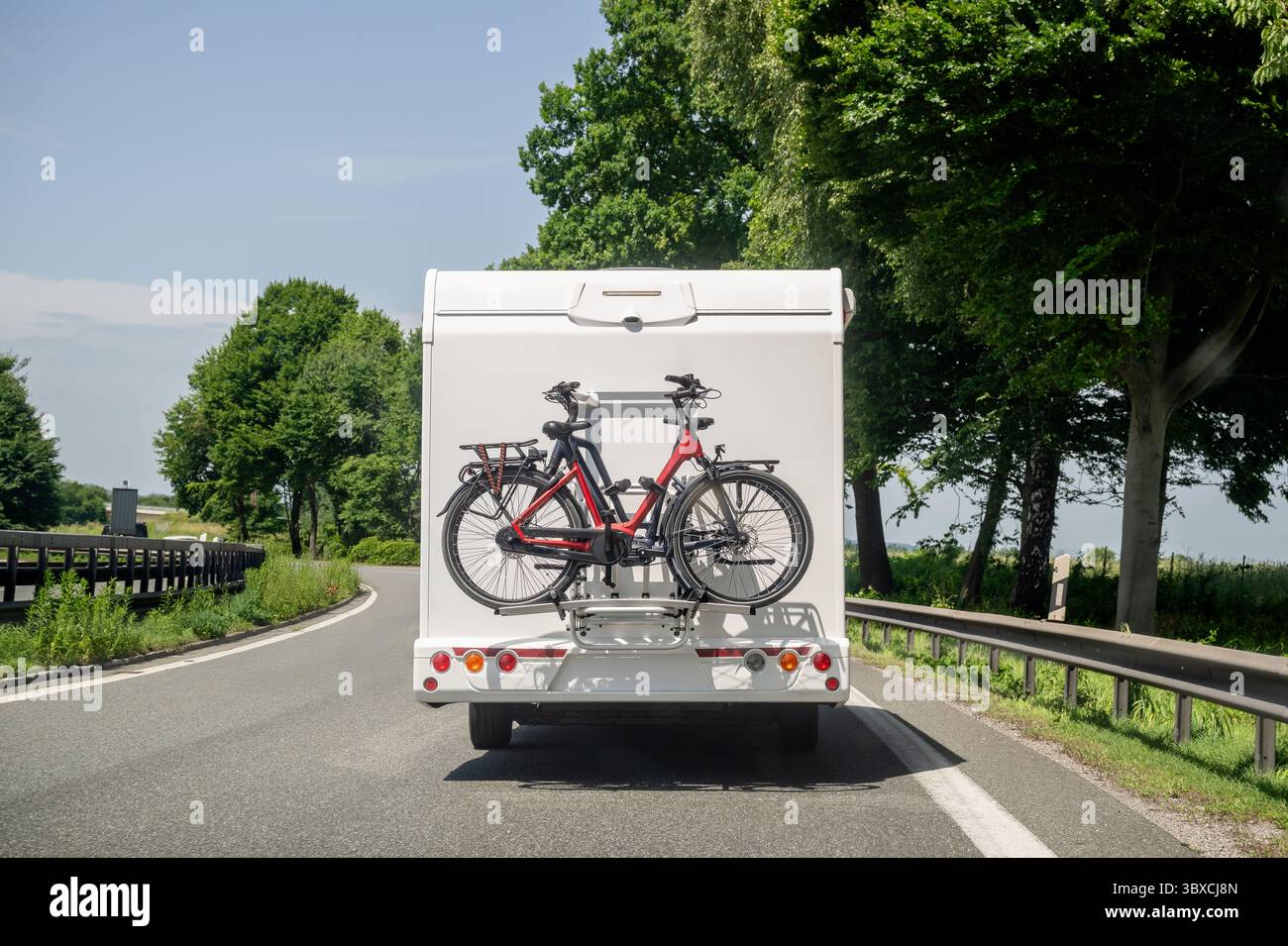 Rear view of a camper van driving on scenic road with two electric ...