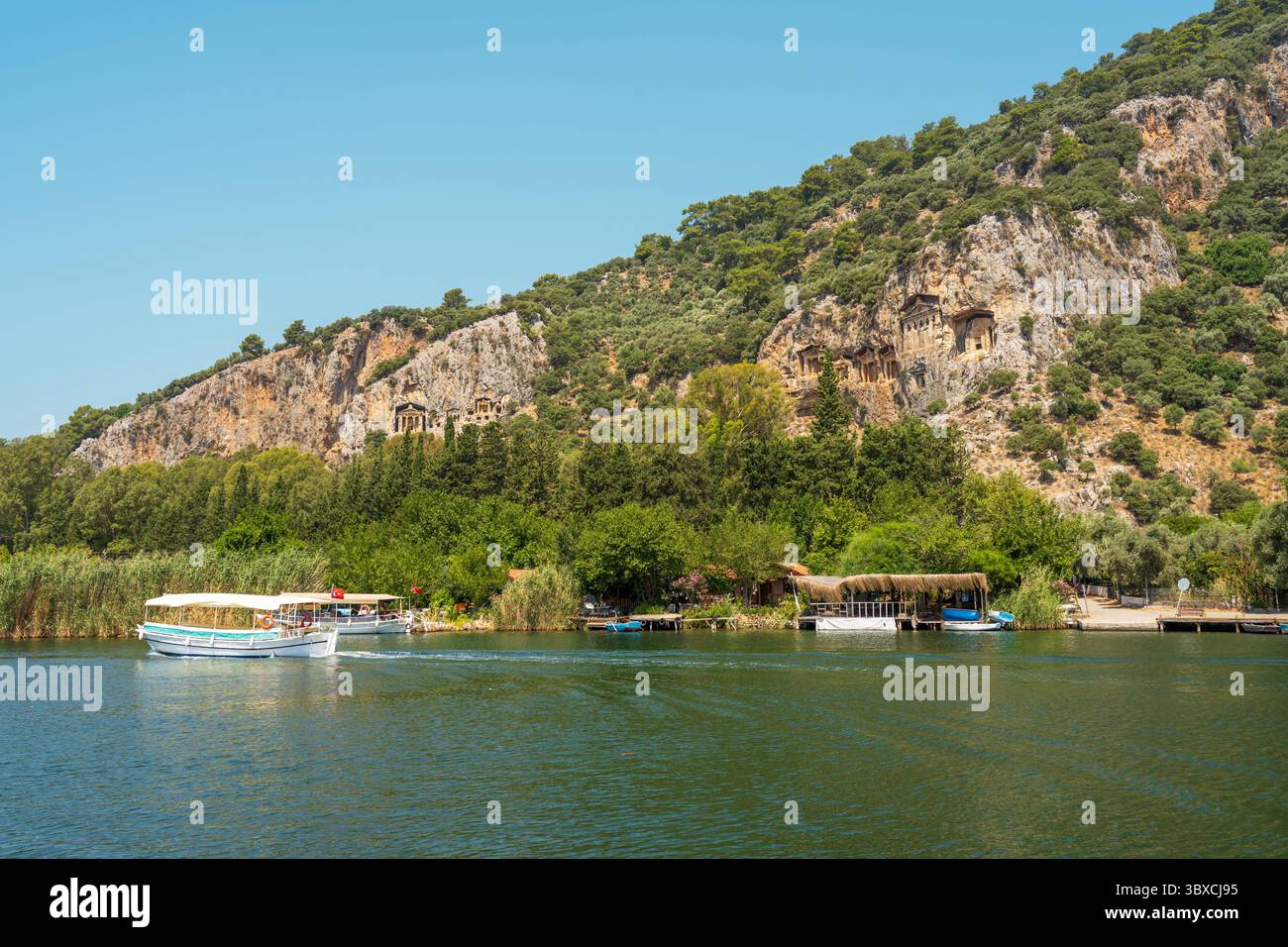 Tour boat on Dalyan River with view of Kaunos rock tombs on cliffs ...