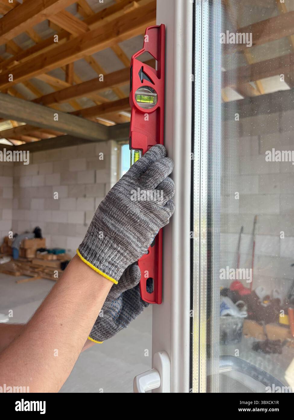 A construction worker's hands check a window frame with a level ...