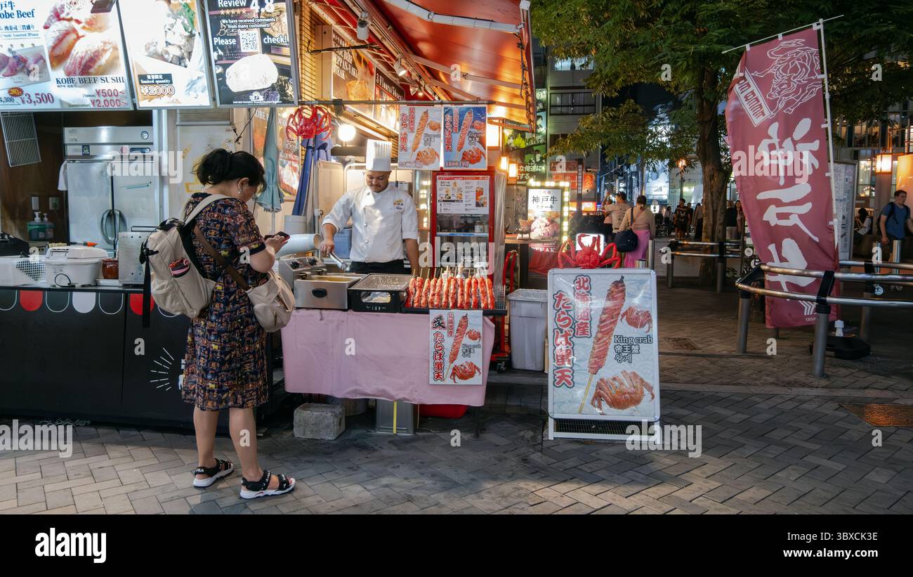 A street food vendor prepares grilled king crab skewers at a night ...