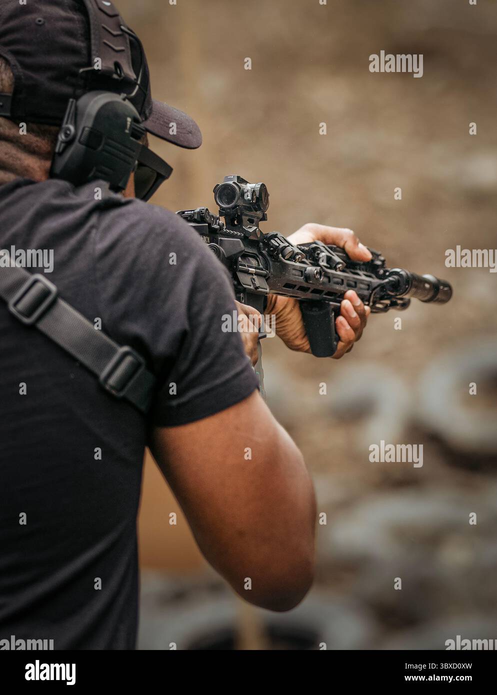 A man in tactical gear aims a rifle at a target during target practice ...