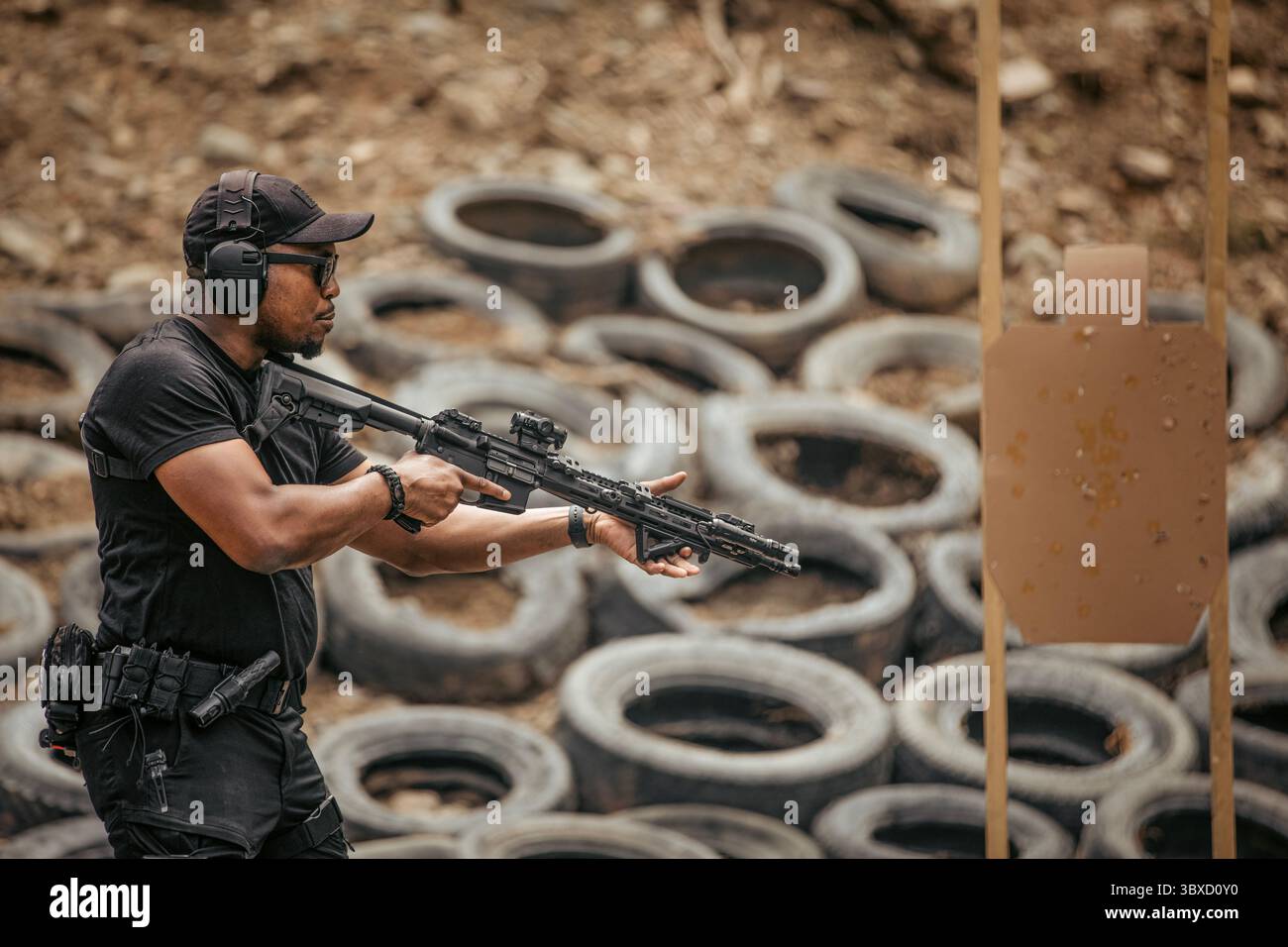 A man in tactical gear aims a rifle at a target during target practice ...