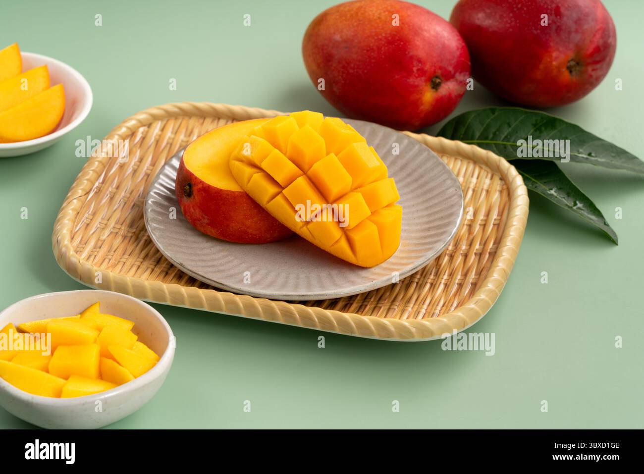 Juicy yellow mango cubes with whole mangoes on a green table background Stock Photo - Alamy