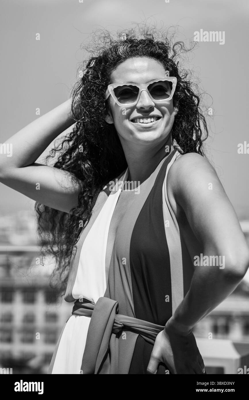Smiling woman in sunglasses poses confidently under sunlight Stock ...