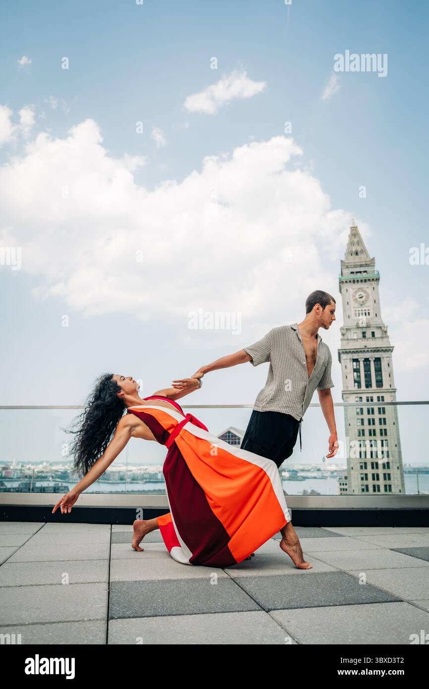Dancers pose dramatically on Boston rooftop with clock tower view Stock ...