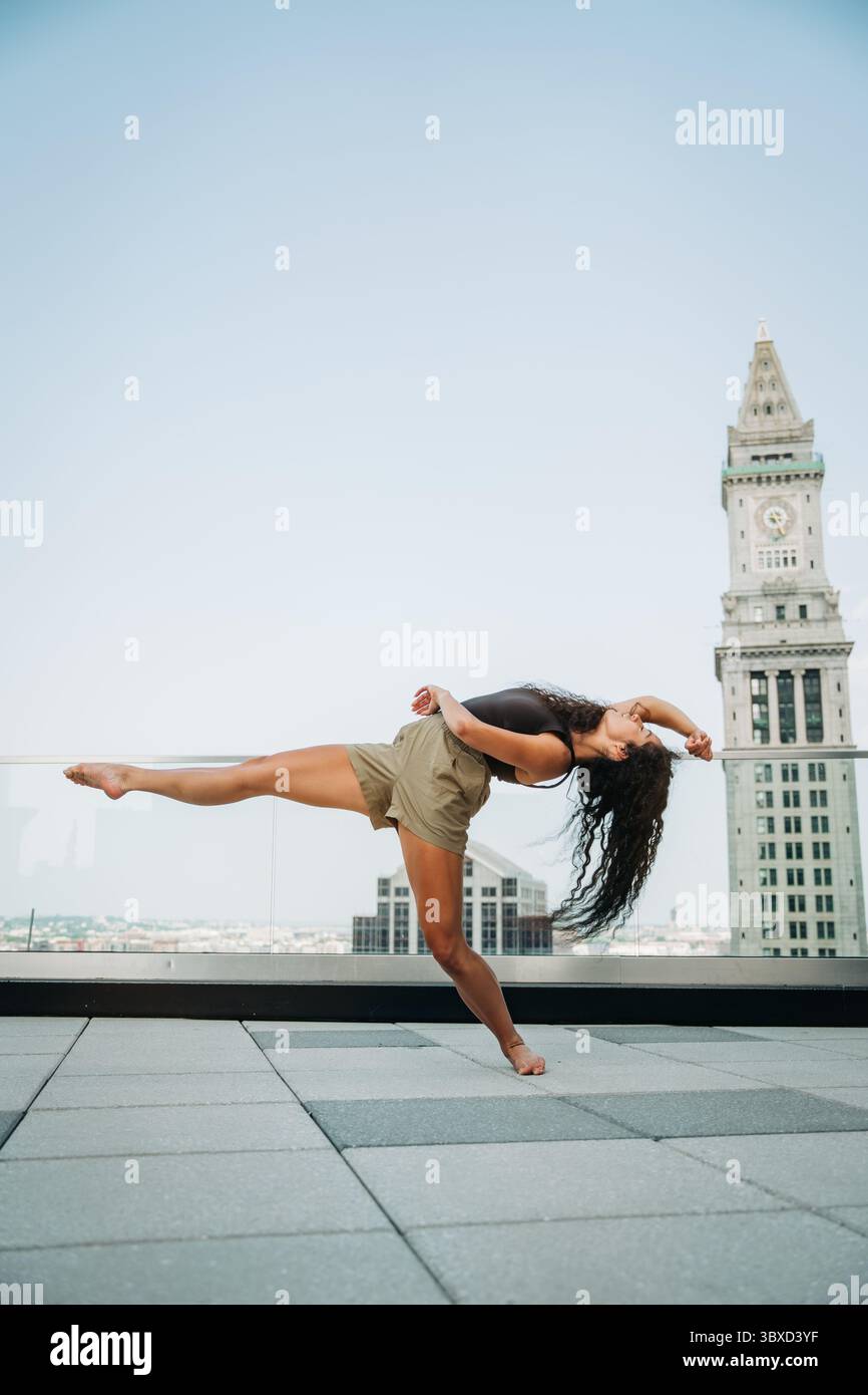Woman dances barefoot on rooftop with Boston clock tower behind Stock ...