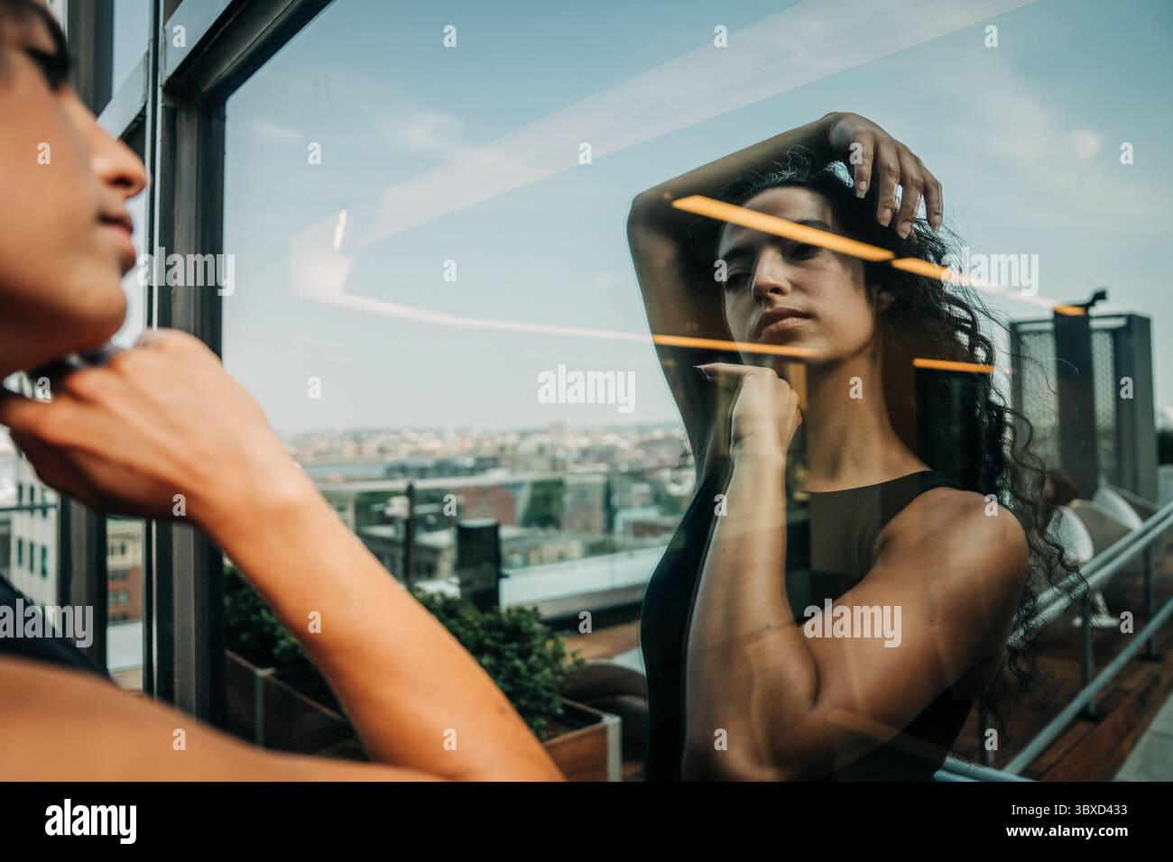 Woman poses thoughtfully in reflection on Boston rooftop glass Stock ...
