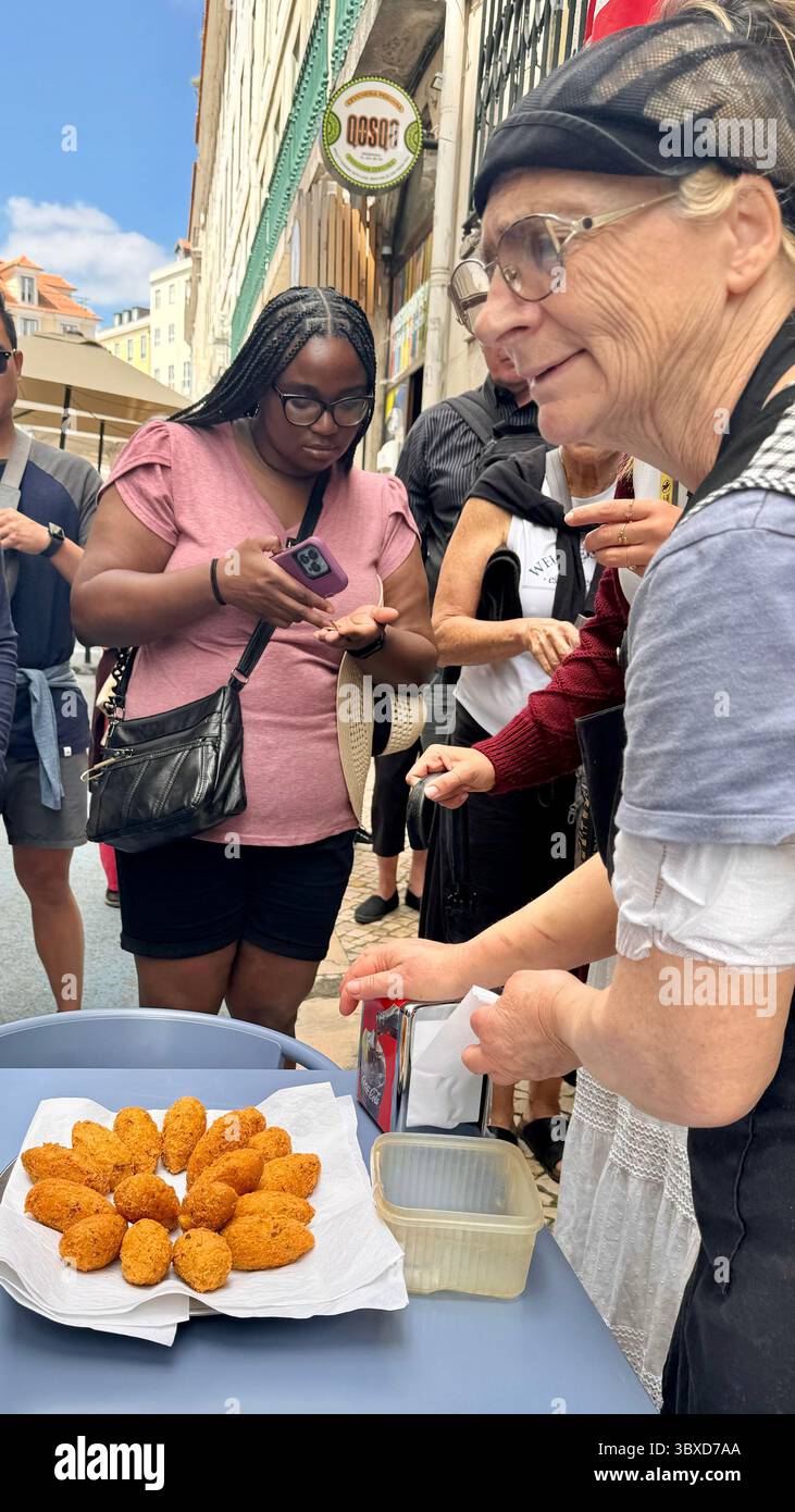 Portuguese woman giving samples of croquettes to a group of tourists ...